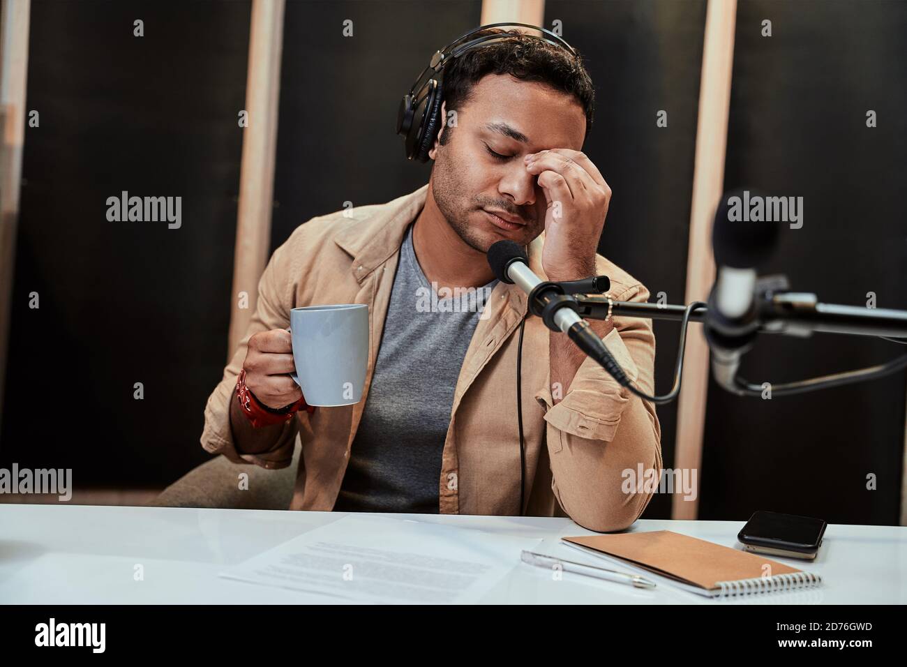 Portrait of young male radio host in headphones looking tired ...