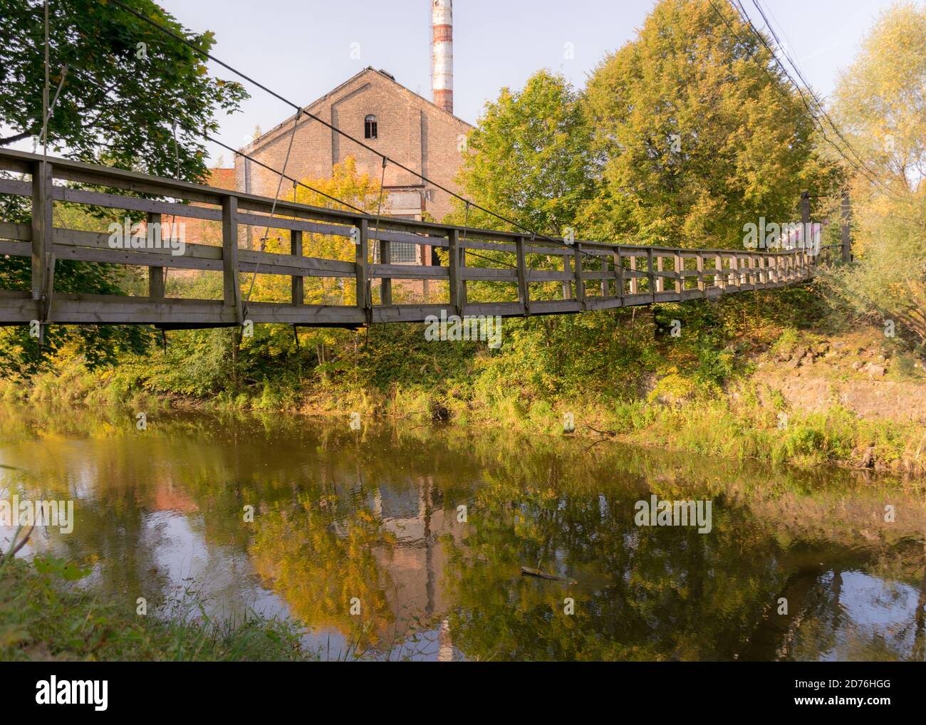 picture with wooden bridge over the river, trees and shrubs in the ...
