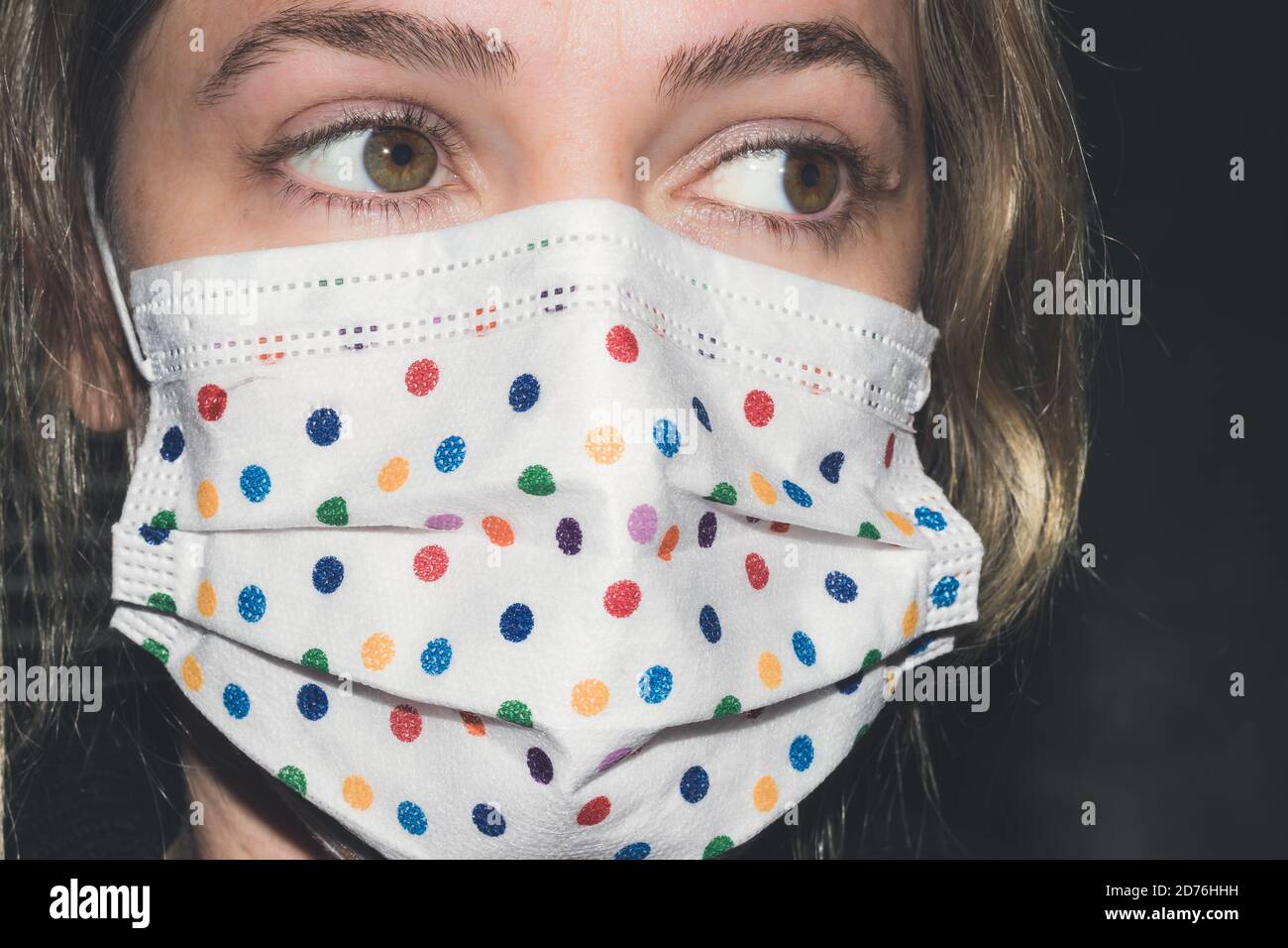 Close-up of woman face wearing a medical mask with colorful dots ...
