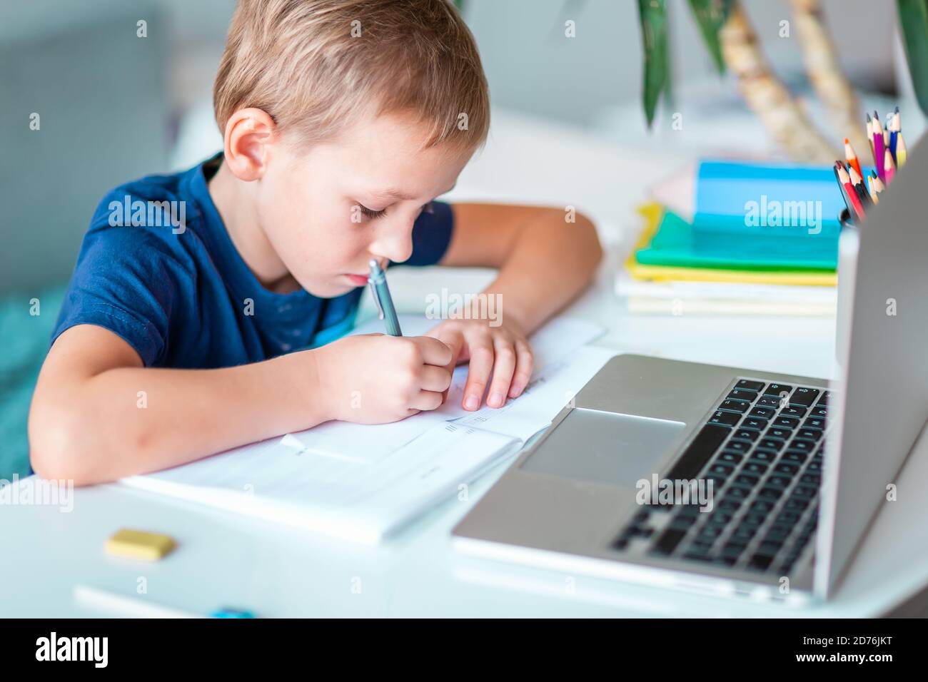Closeup of little young school boy working at home with a laptop and ...