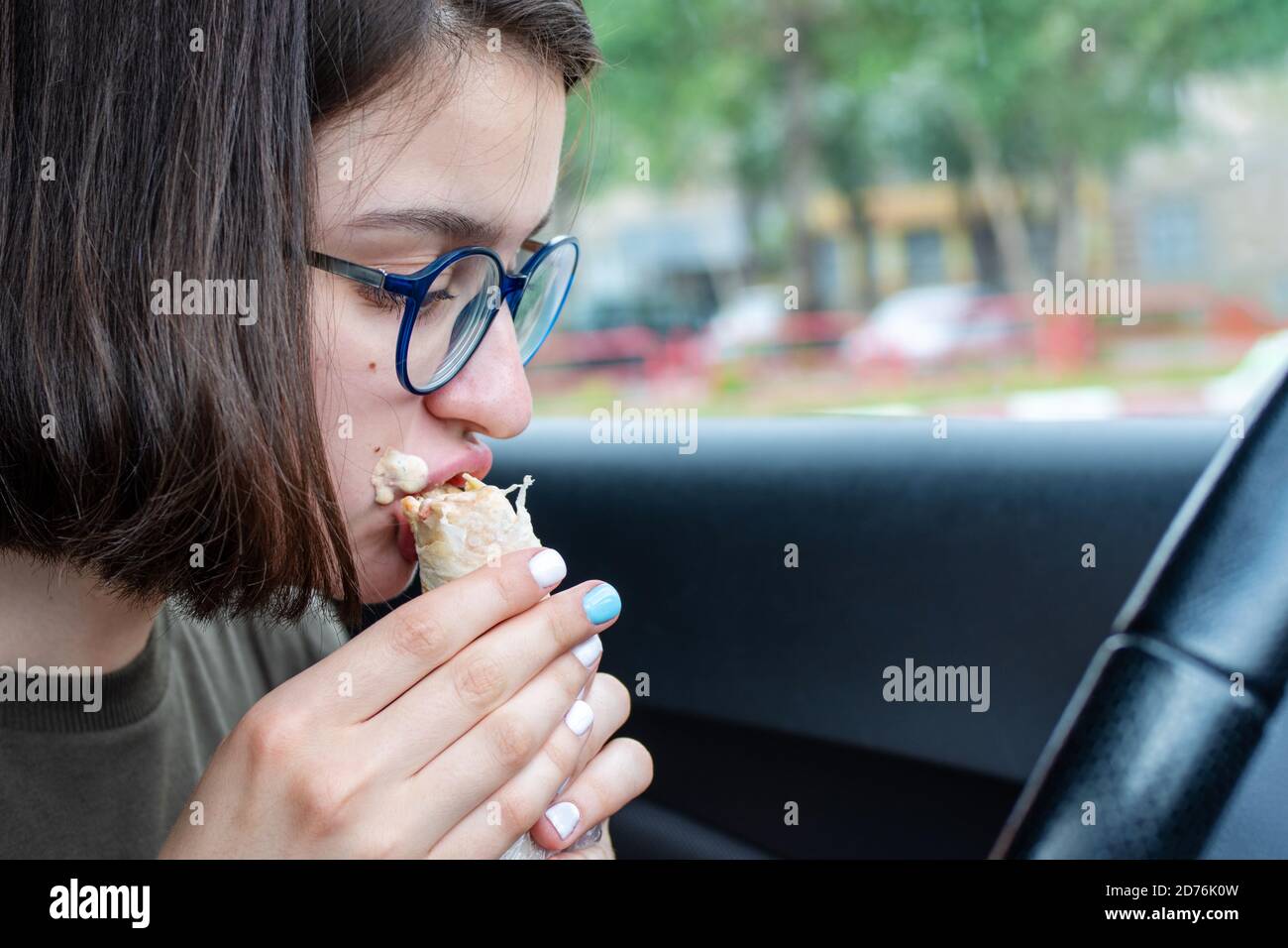 Young beautiful woman eating fast food in the car. Break. Dinner in the ...