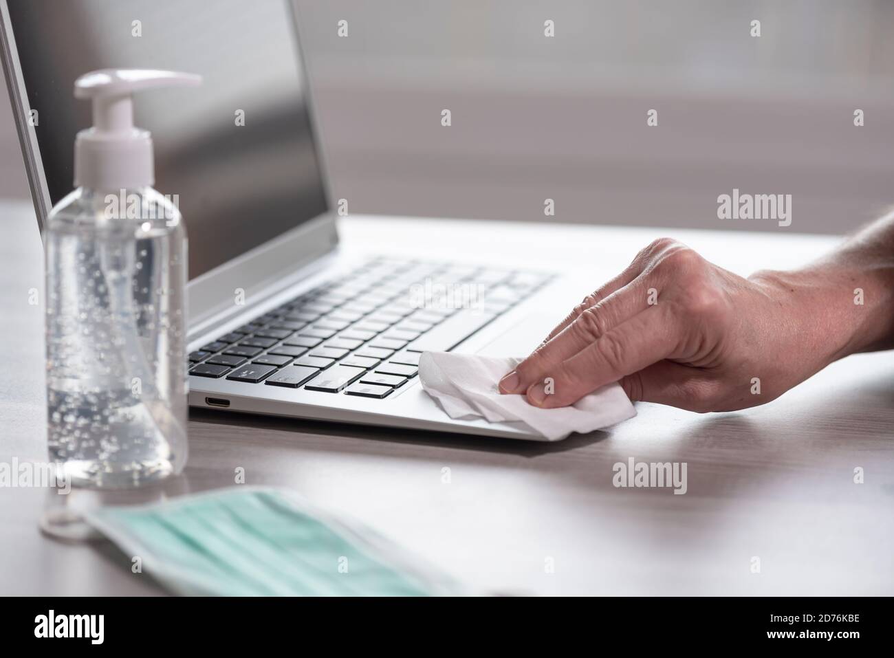 Woman disinfecting laptop keyboard with antibacterial wipe; prevention ...