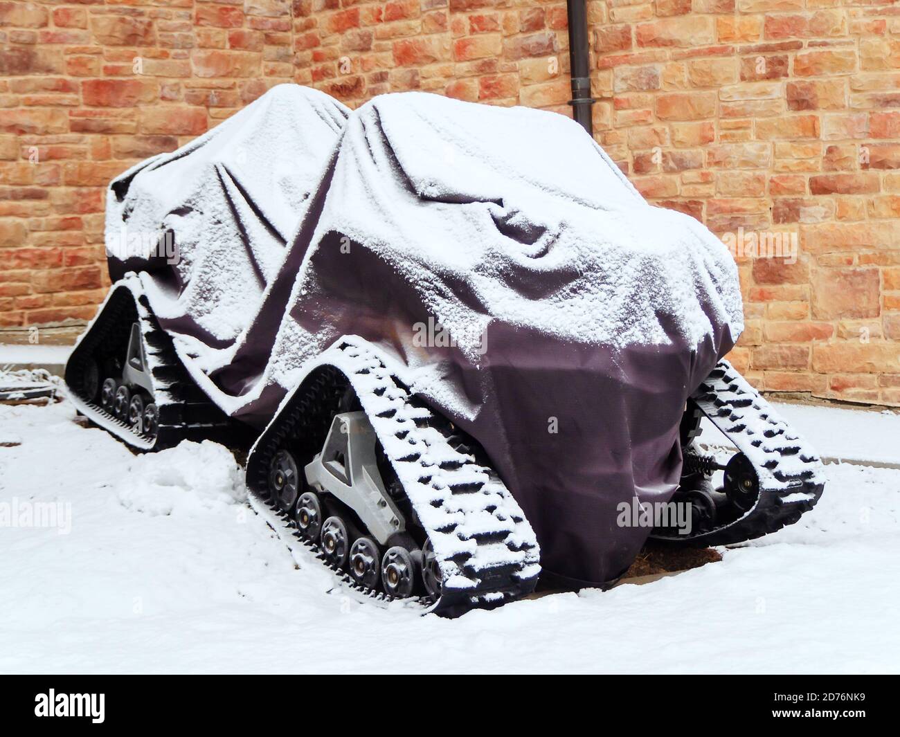 The tuning tracked quad bike covered with a cape stands near the stone ...