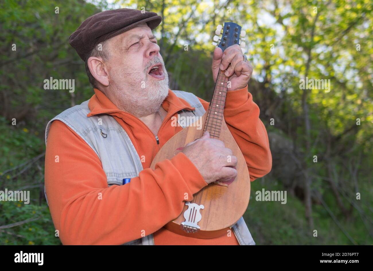 Nice outdoor portrait of Caucasian senior man playing mandolin while ...