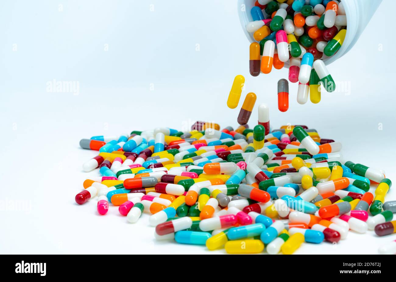 Pouring capsule pills from plastic drug bottle to white table. Pile of ...