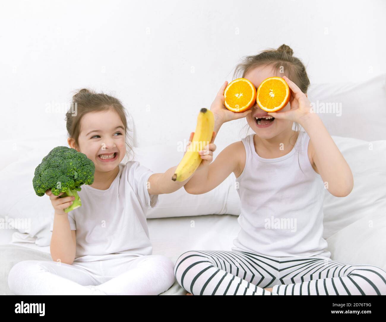 Happy two cute children play with fruits and vegetables on a light ...