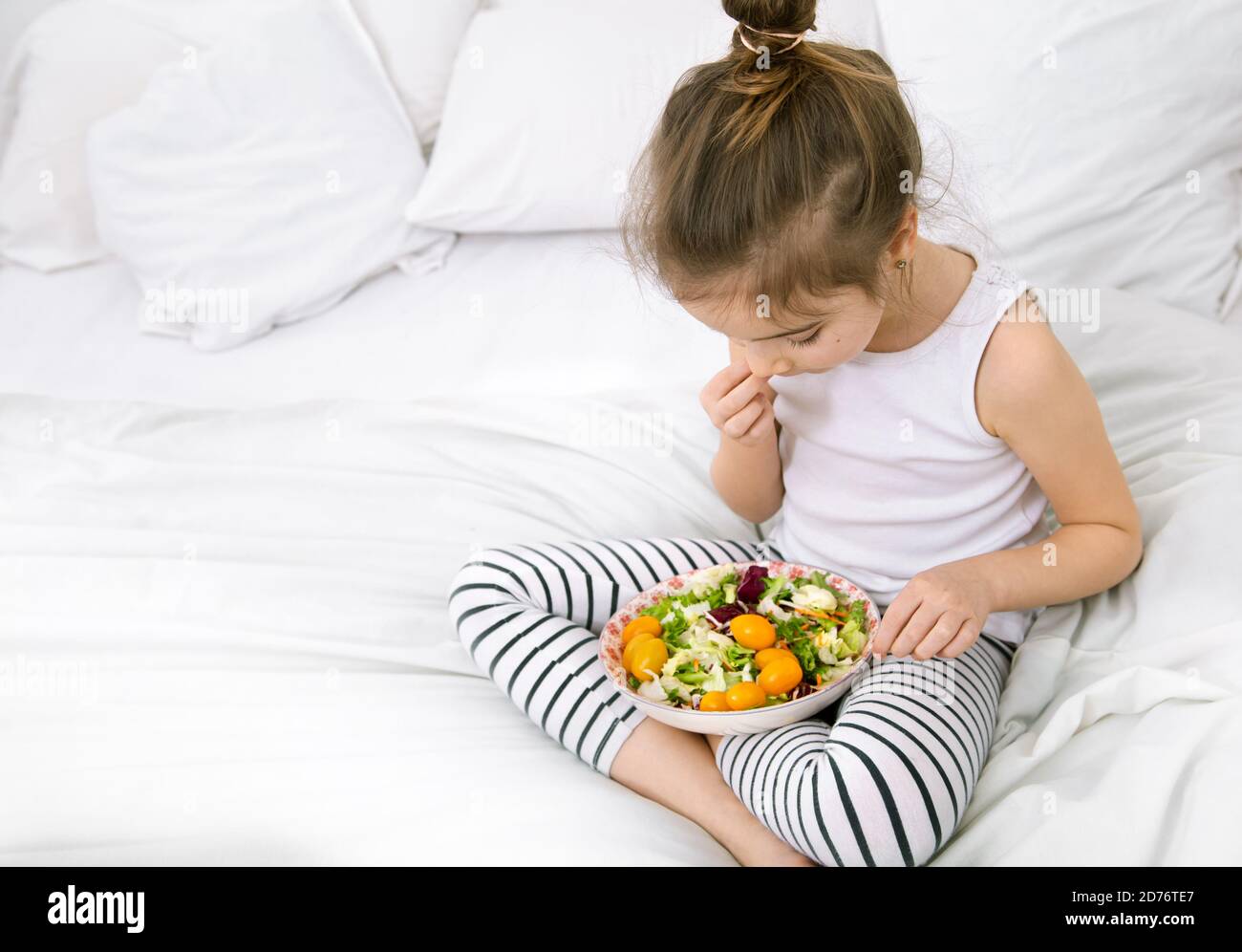 Cute little girl with fruits and vegetables on a light background ...