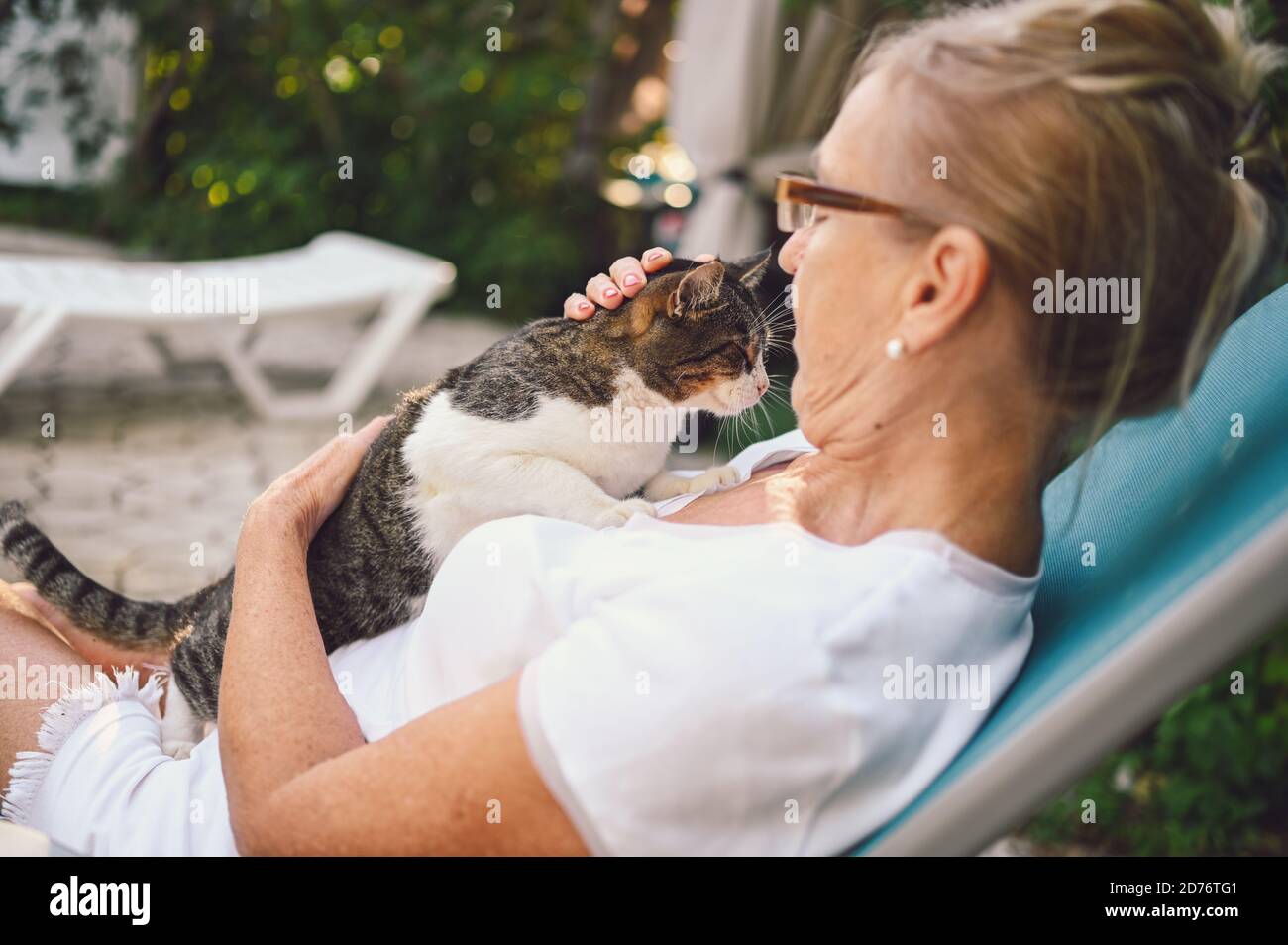 Happy smiling senior elderly woman in glasses relaxing in summer garden ...