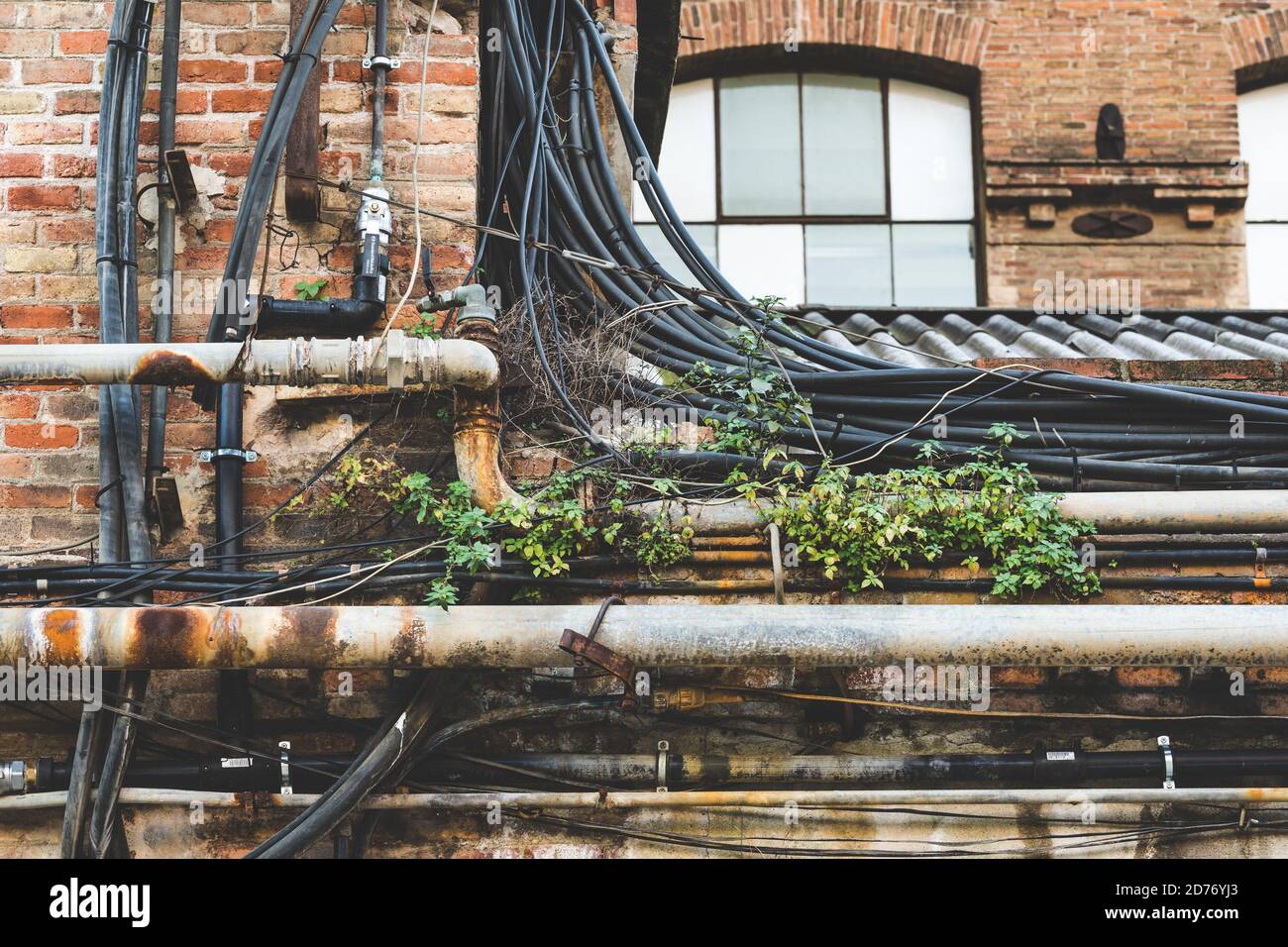 Rusty pipes, cabling and weeds on the roof of an old factory Stock ...