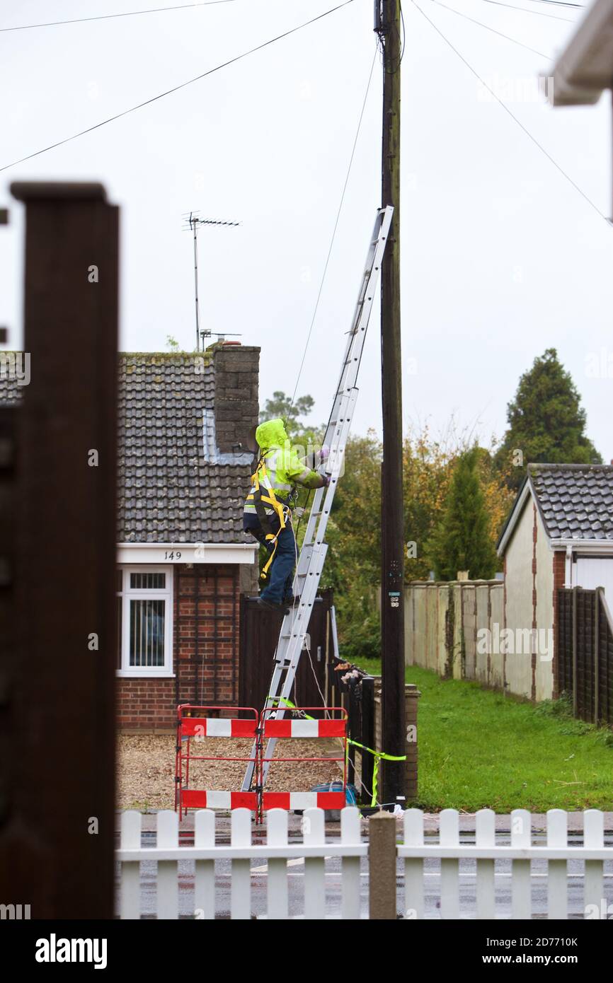 Open reach telecommunications engineer at work up a ladder, he is ...