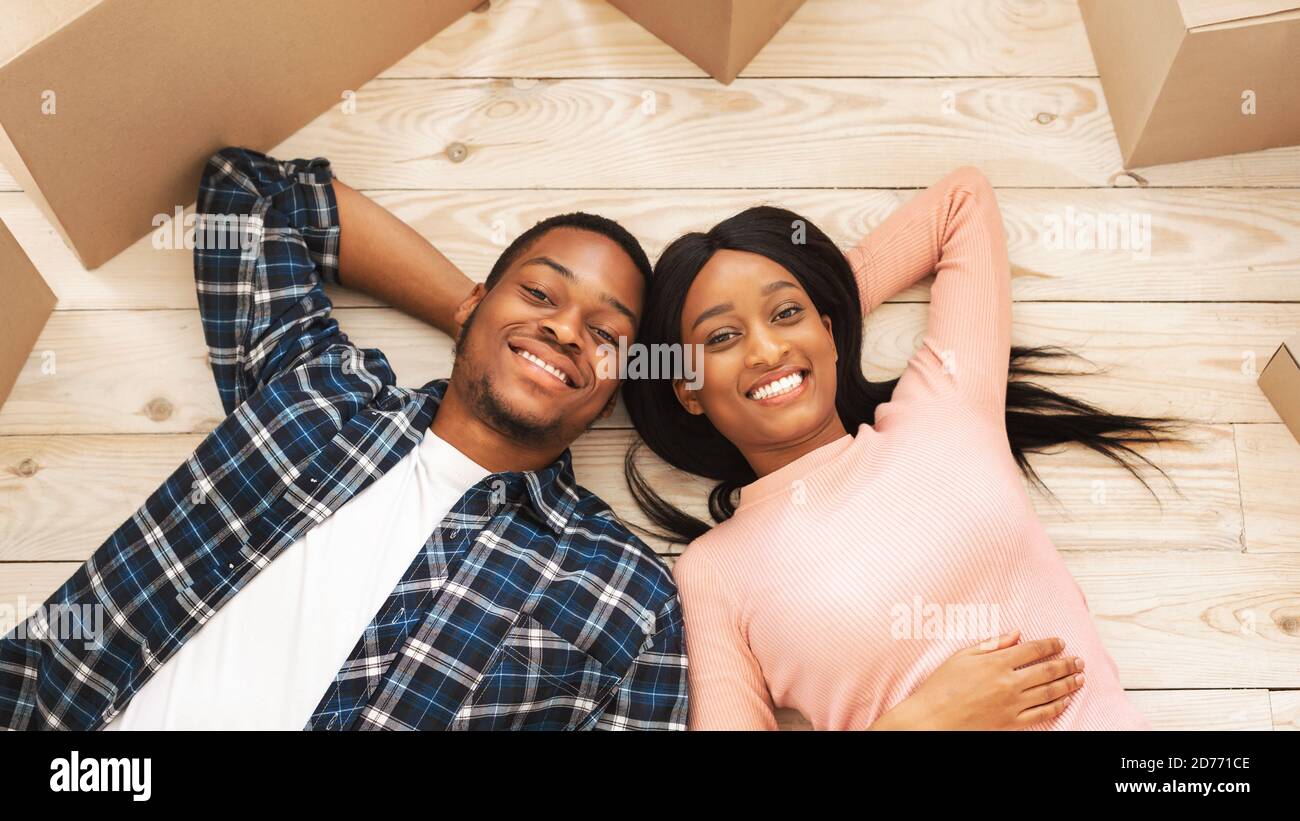 Positive young African American family with carton boxes having rest on ...