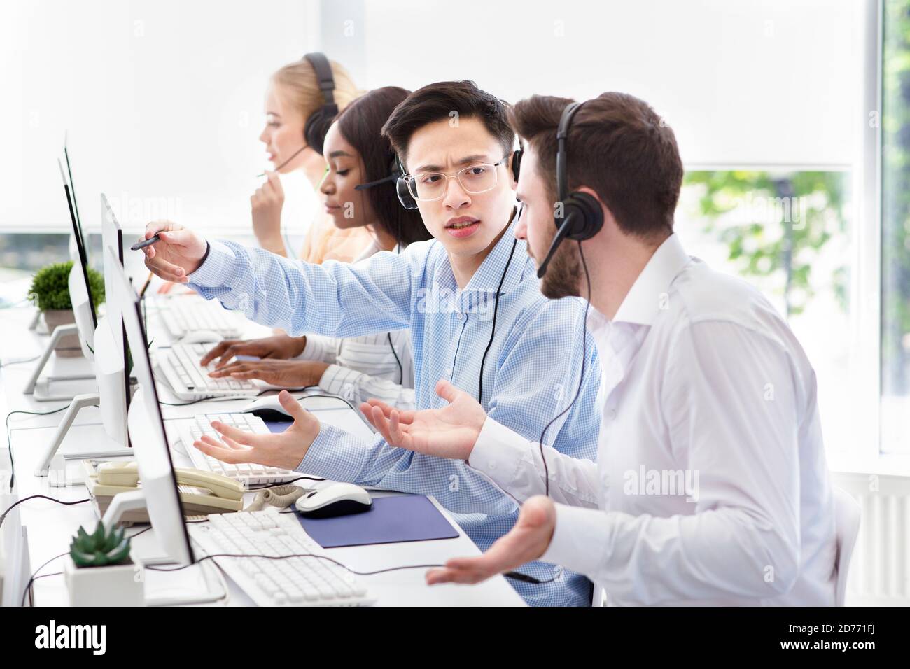 User support service concept. Hotline operator helping his coworker at ...