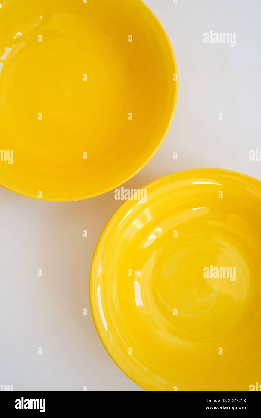 Two yellow plates on a white background Stock Photo - Alamy