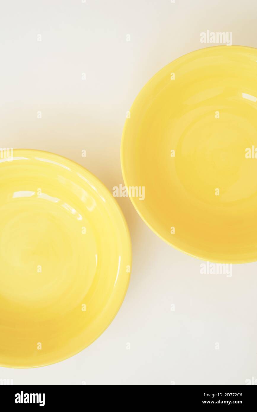 Two yellow plates on a white background Stock Photo - Alamy