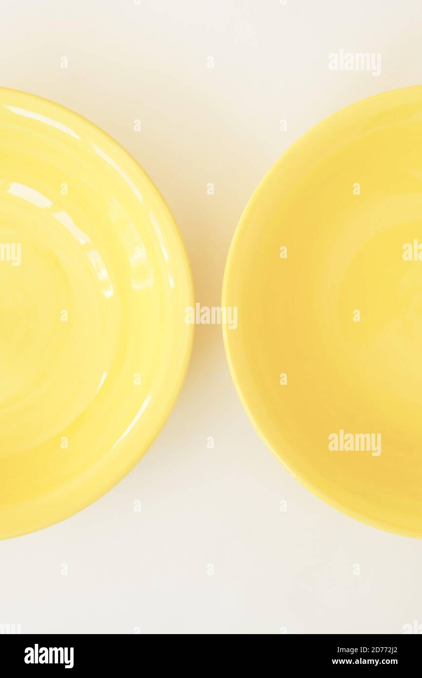 Two yellow plates on a white background Stock Photo - Alamy