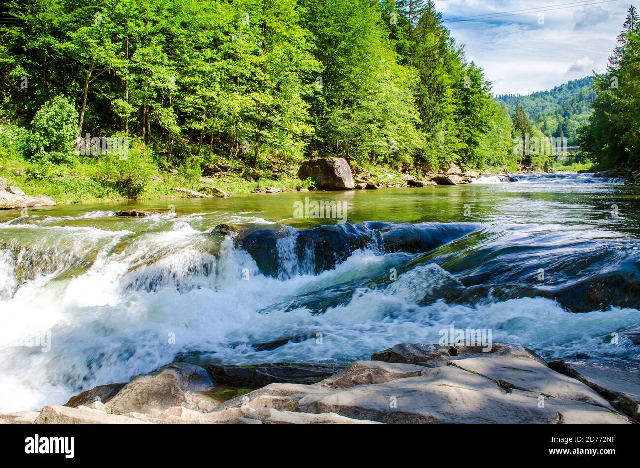 mountain river with a rapid current of rocks with a waterfall in summer ...