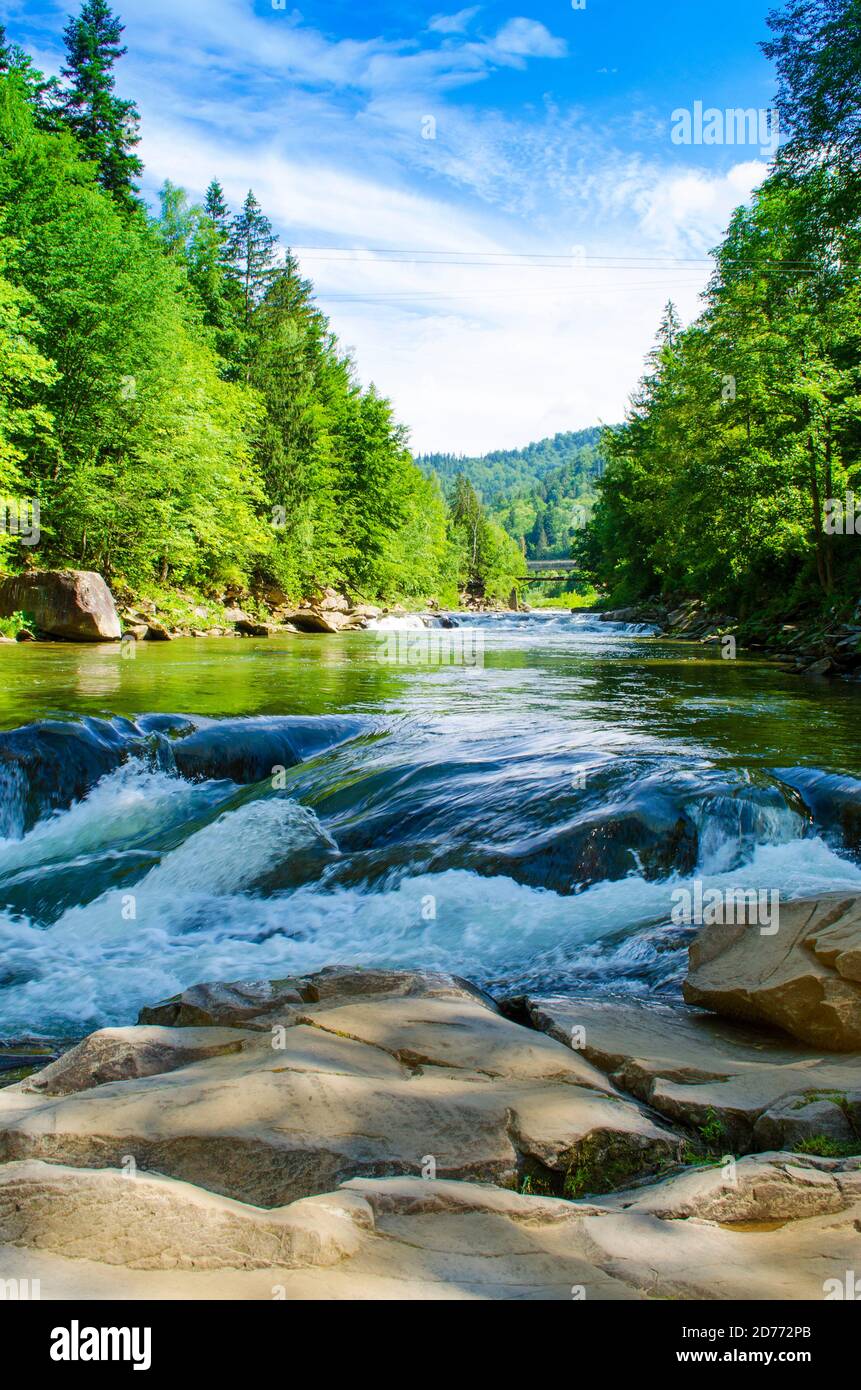 mountain river with a rapid current of rocks with a waterfall in summer ...