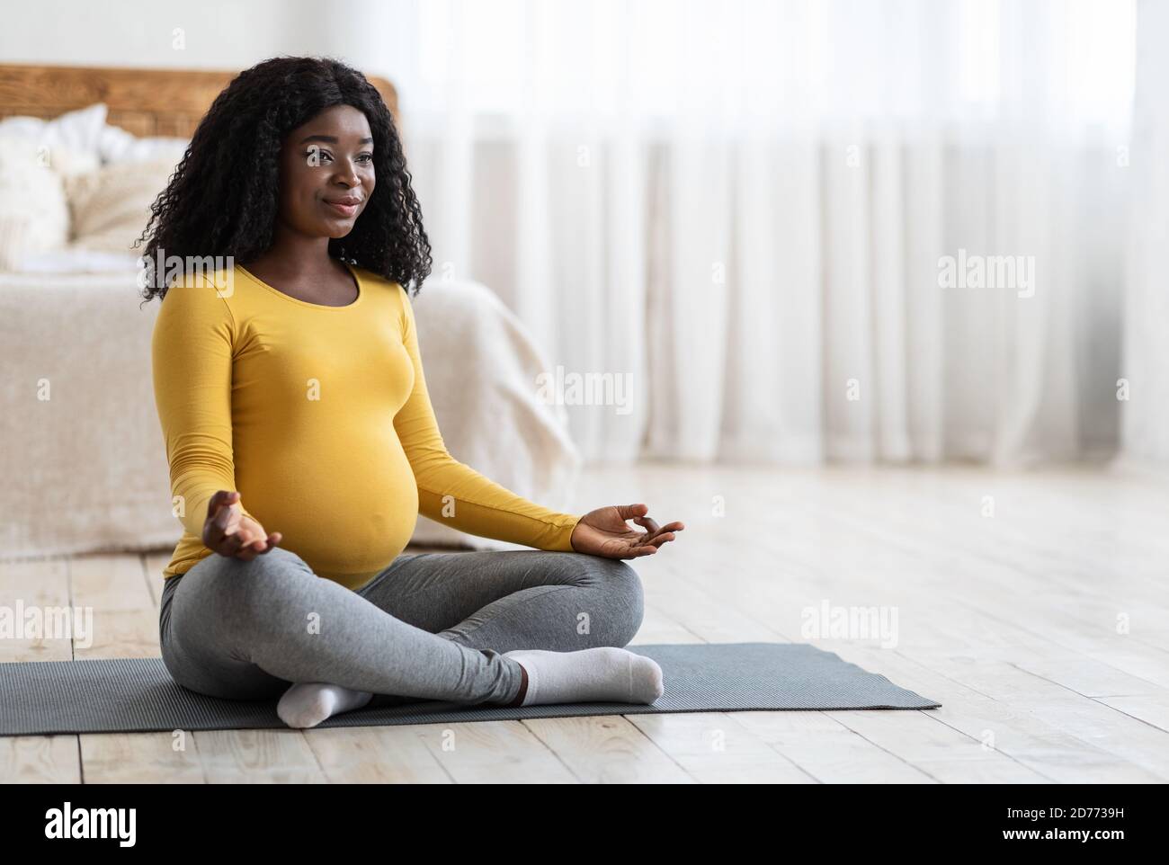 Pregnant african woman meditating in lotus position at home Stock Photo ...