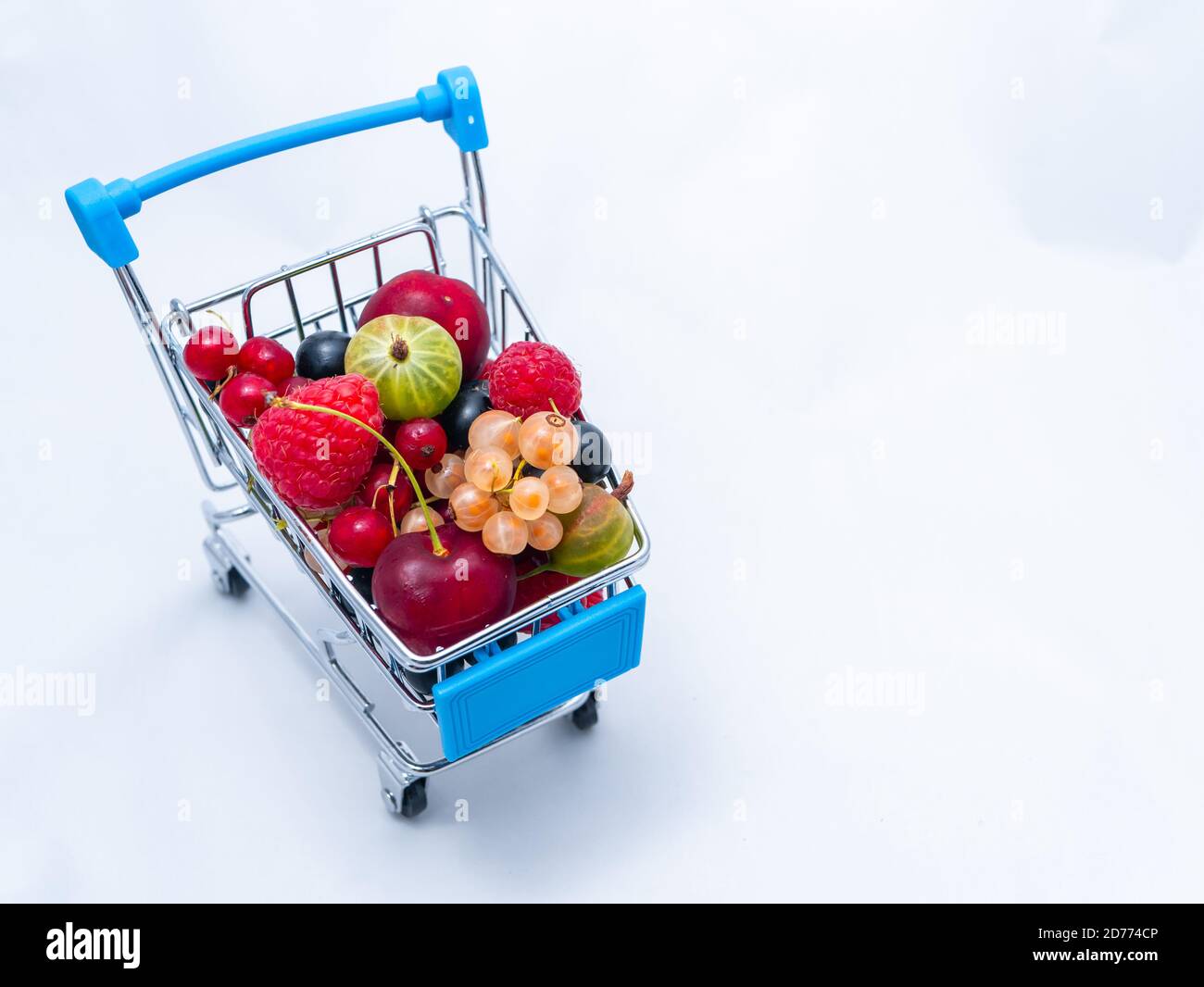 Mini grocery cart filled with fresh vitamin berries isolated on white ...