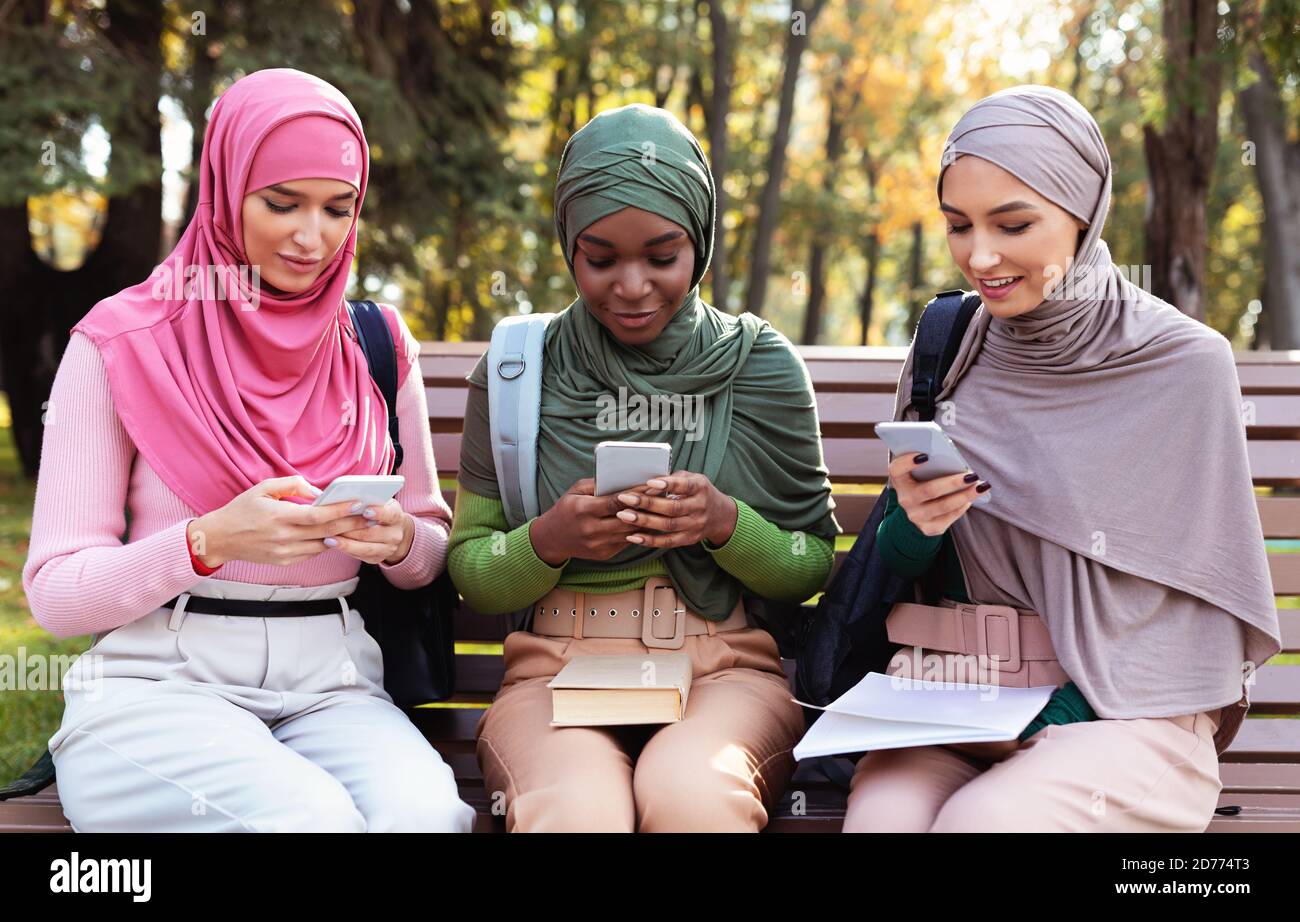 Three Muslim Ladies Women Using Cellphone Texting Sitting Outside Stock ...