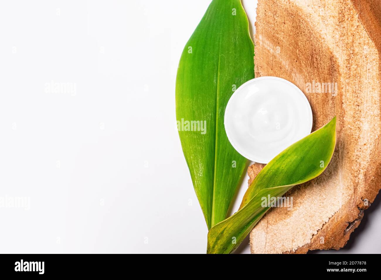 Cosmetic cream on natural white stone with green leaves on white bright ...