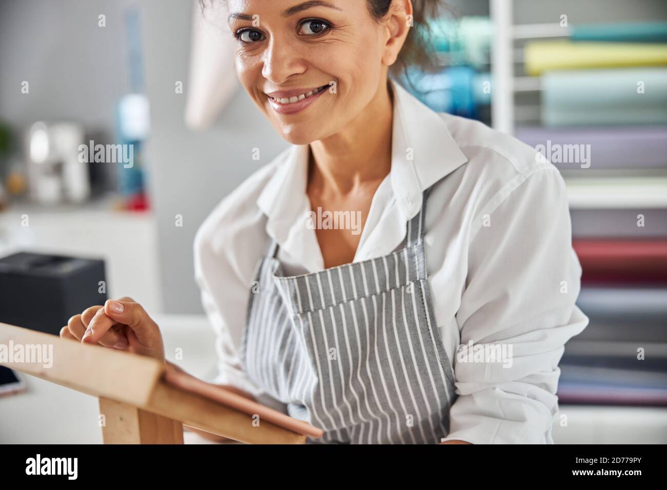 Smiley lady clicking on a tablet while working in shop Stock Photo - Alamy