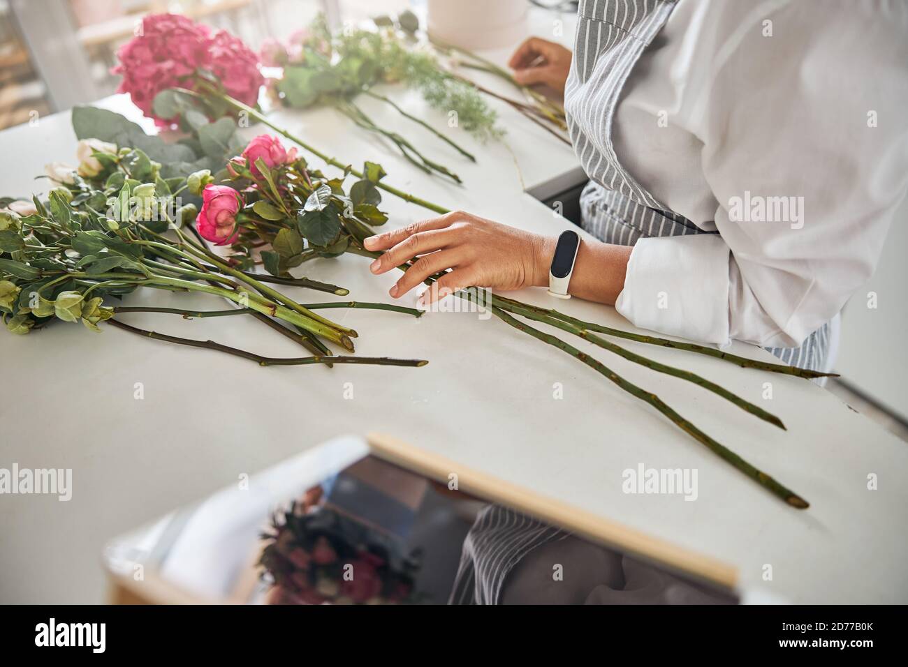 Skilled flower shop worker touching flowers on the table Stock Photo ...