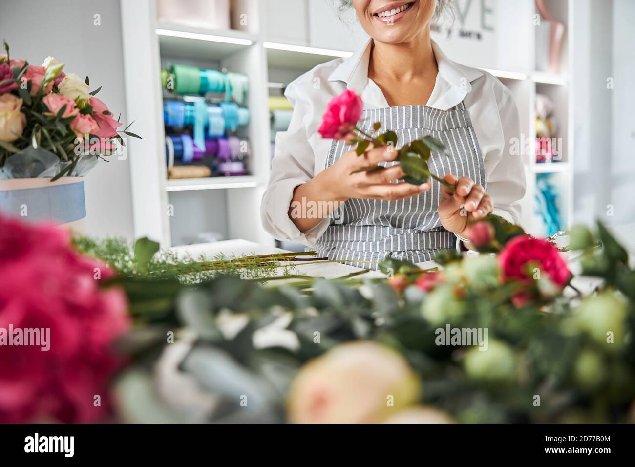 Female flower shop worker posing with roses at workplace Stock Photo ...