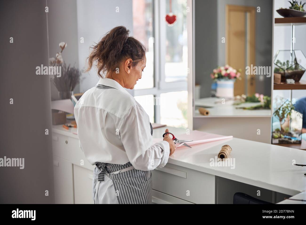Beautiful florist lady cutting paper for wrapping flowers Stock Photo ...