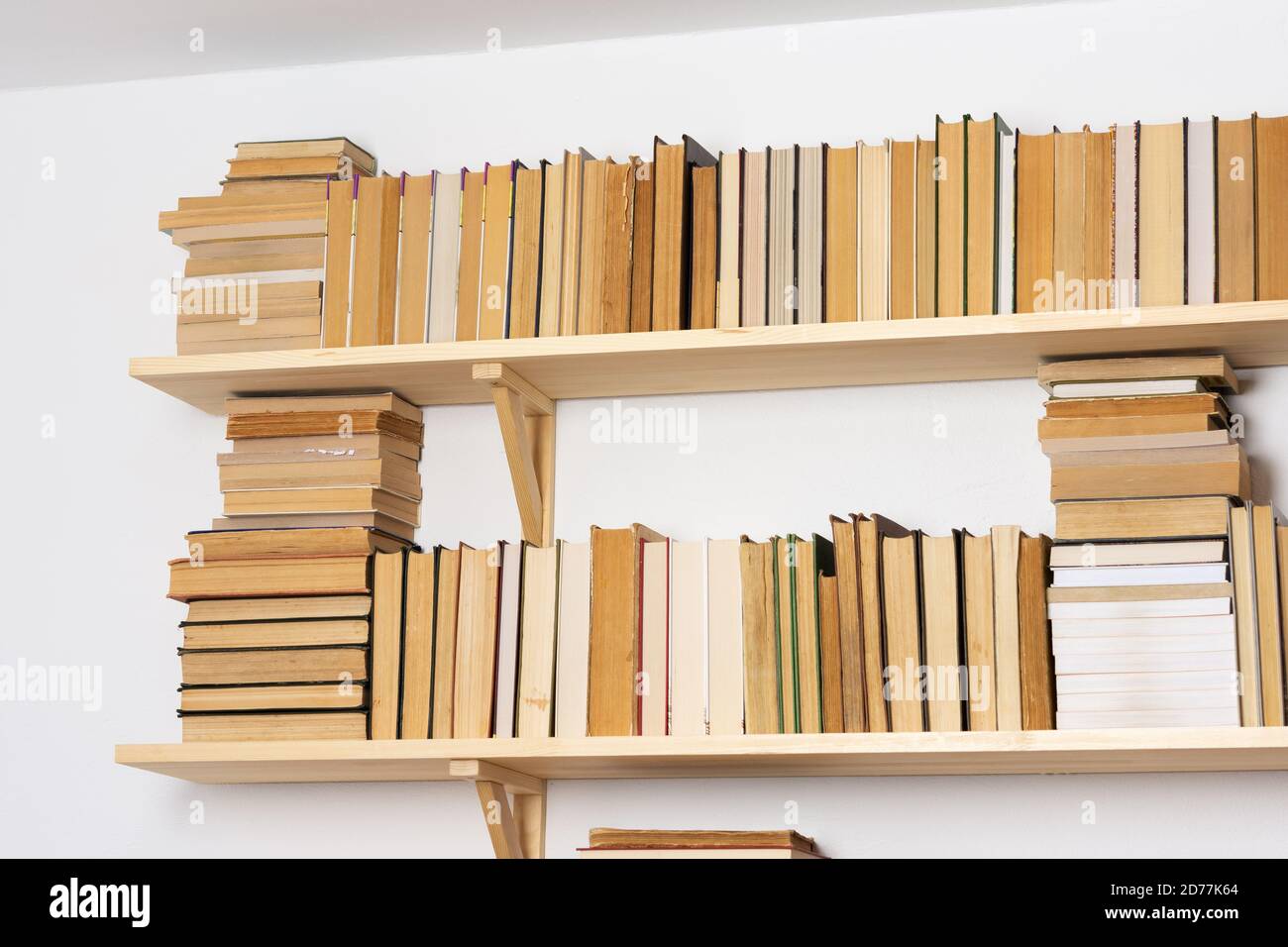 Light wooden bookshelves with hardback overturned books in white ...
