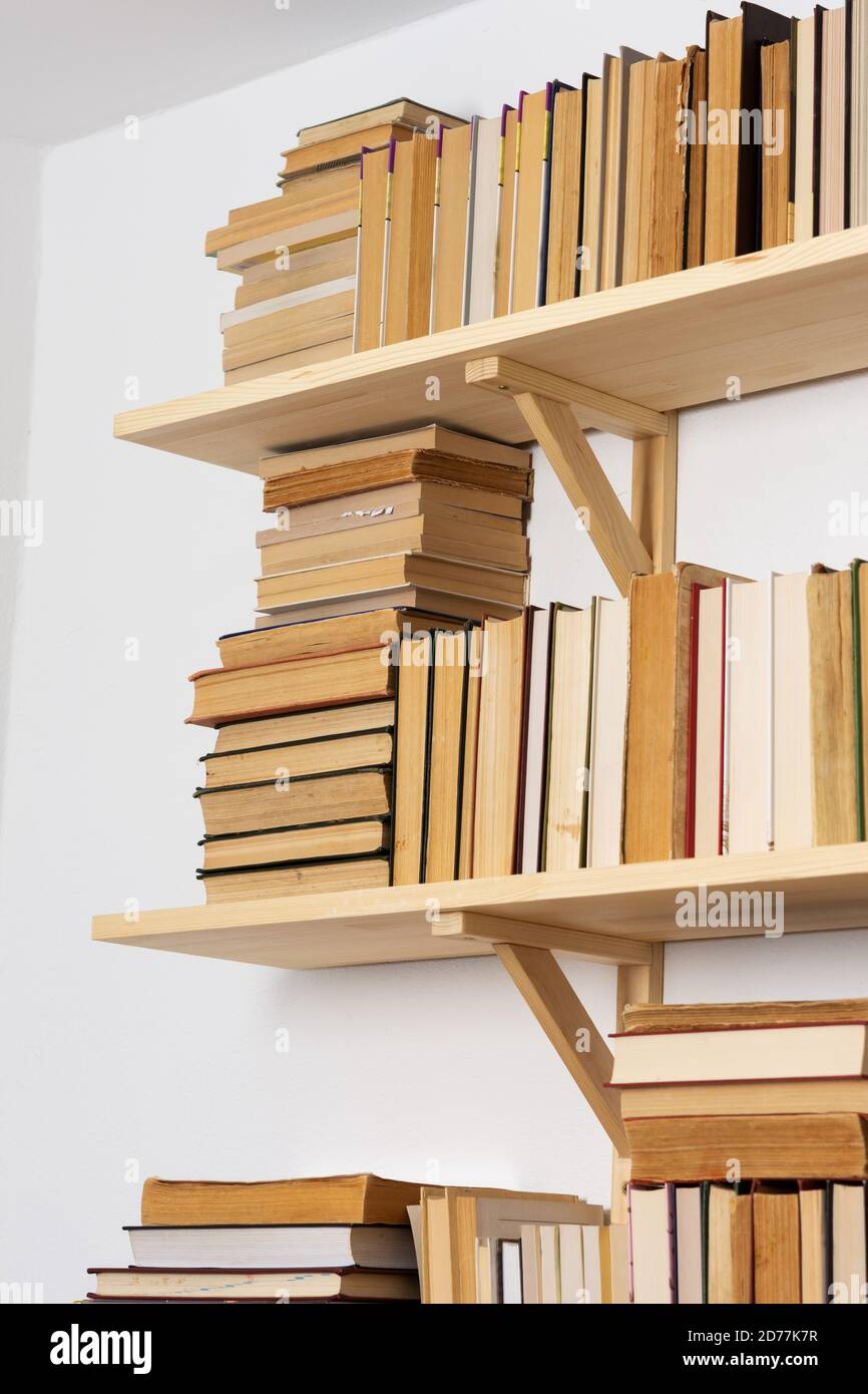 Light wooden bookshelves with hardback overturned books in white ...