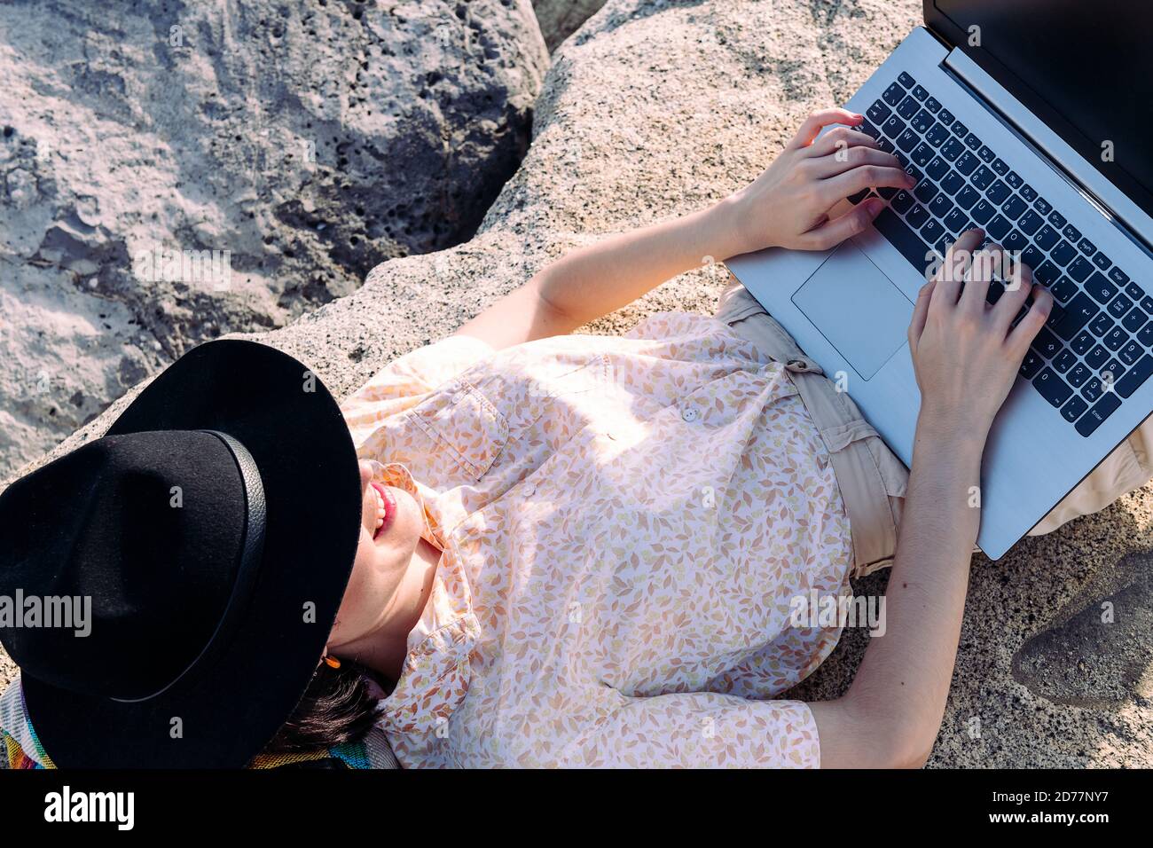 top view of a young traveler woman working lying down with laptop ...