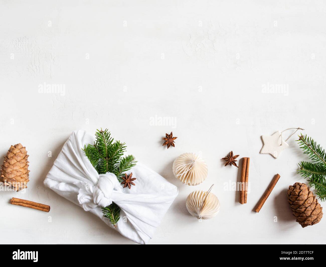 Flat lay fabric wrapped gift with fir tree branch and nature decor ...