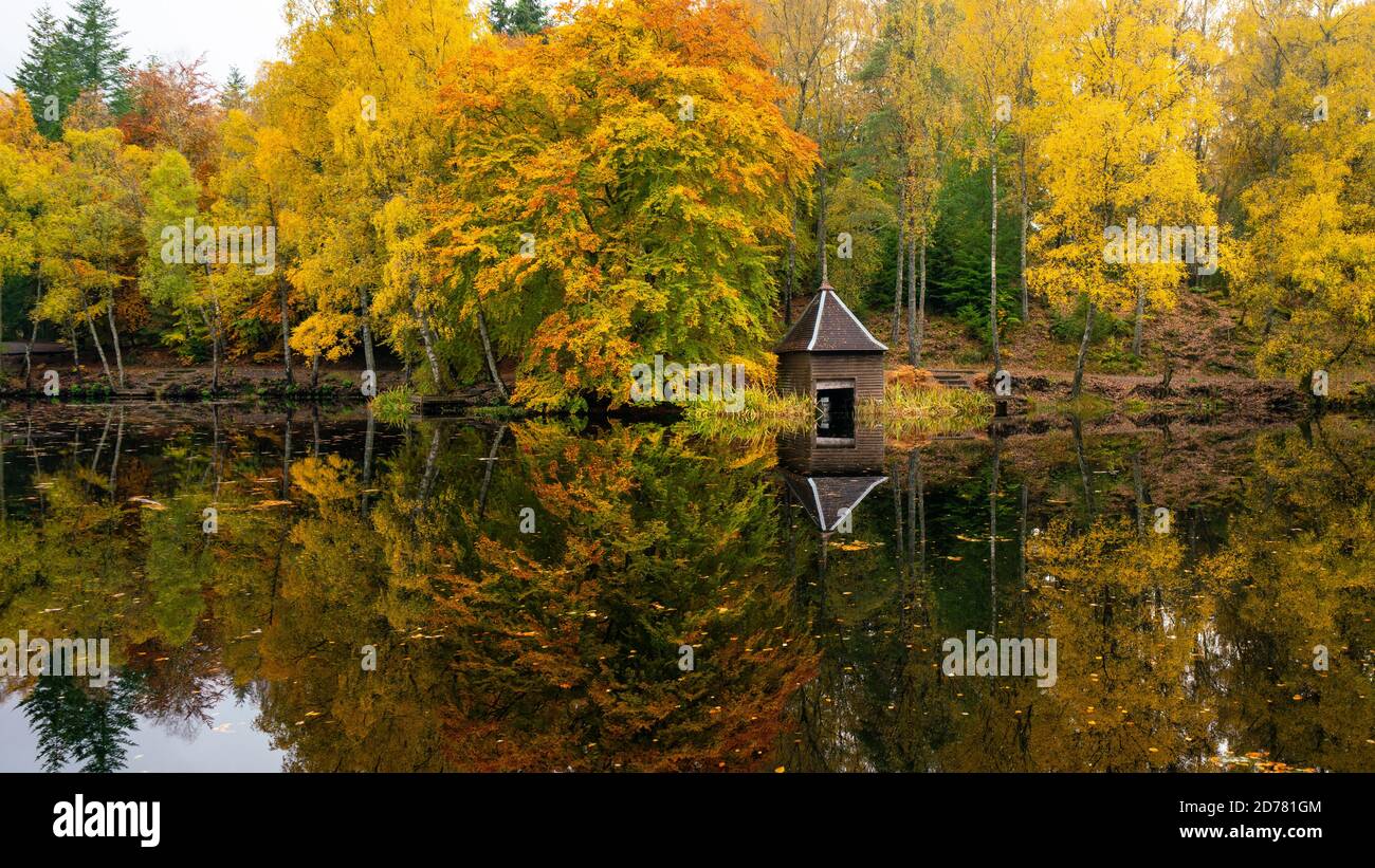 Autumn colours on woodland foliage and wooden boathouse at Loch Dunmore ...