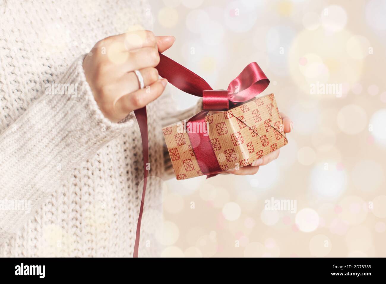 Young woman unties a Gift box close up over lights bokeh Stock Photo ...