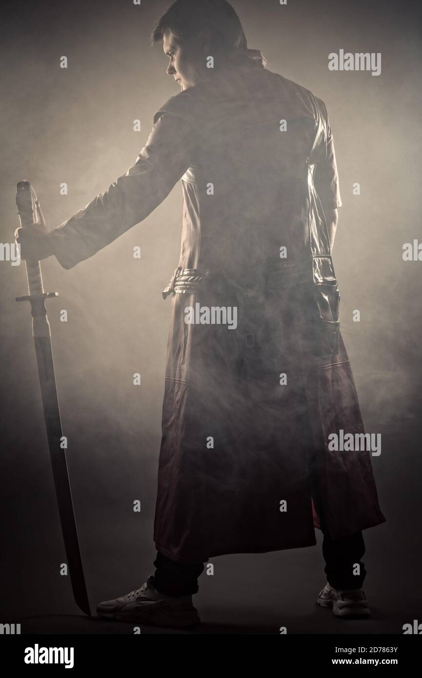 person in jacket with sword standing back in smoke Stock Photo - Alamy