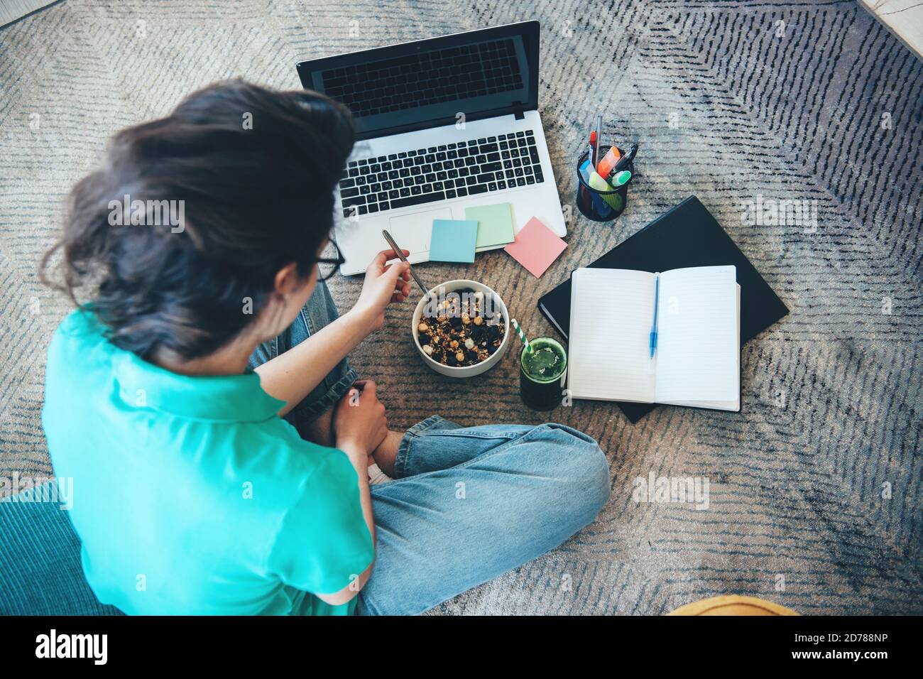 Upper view photo of a caucasian woman eating cereals and doing homework ...