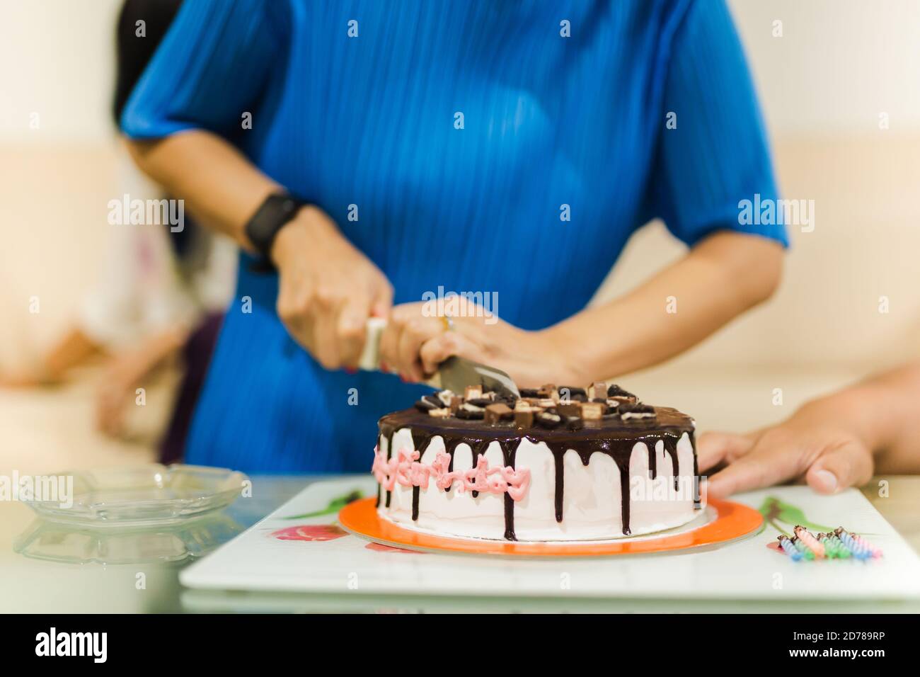 Woman is hand cutting birthday cake together with family Stock Photo ...