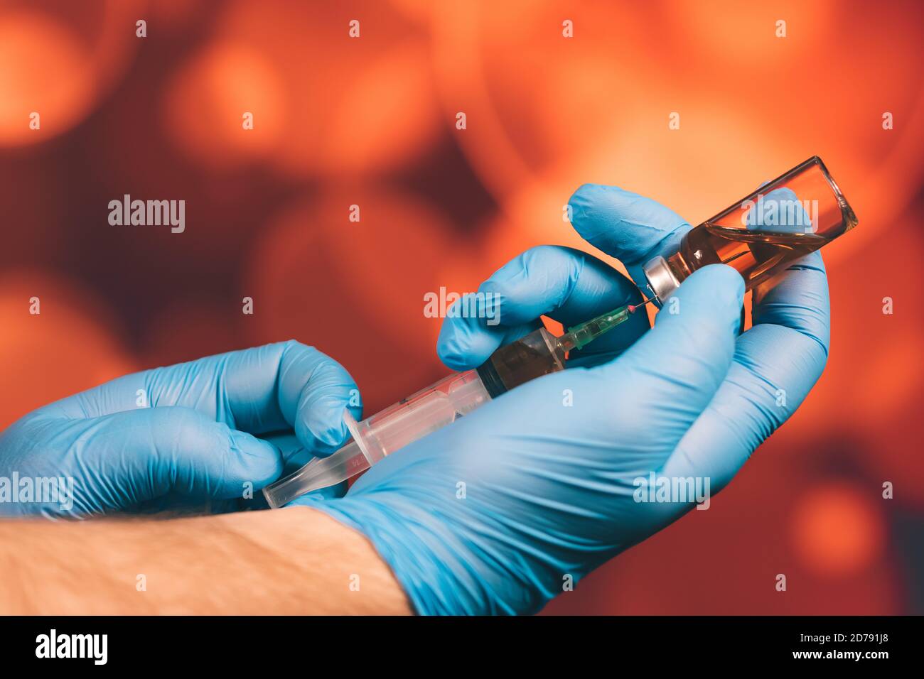 A blue-gloved medical worker draws an ampoule into a syringe. Medical ...
