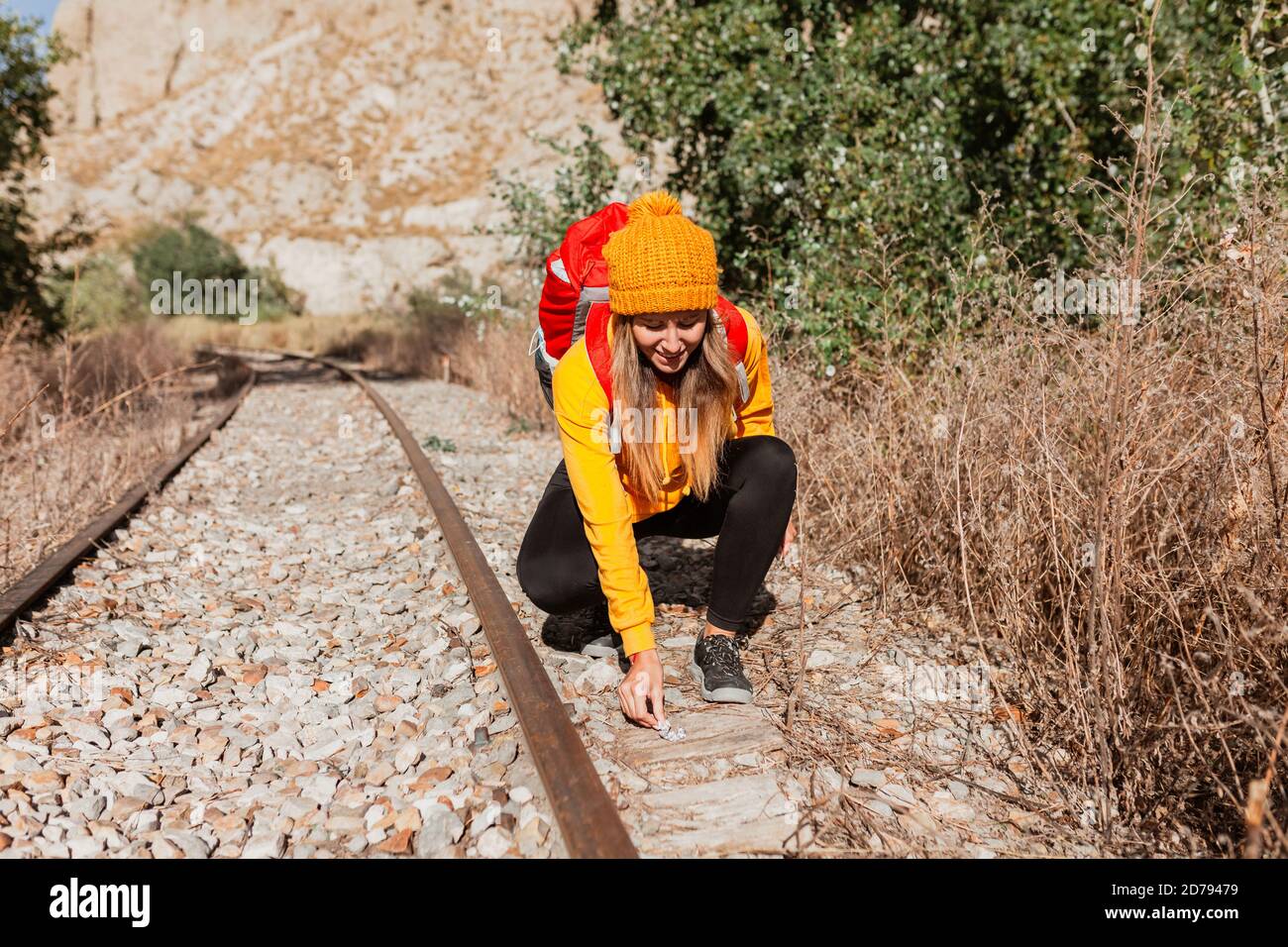 Woman trekking near train tracks picks up trash in nature ...