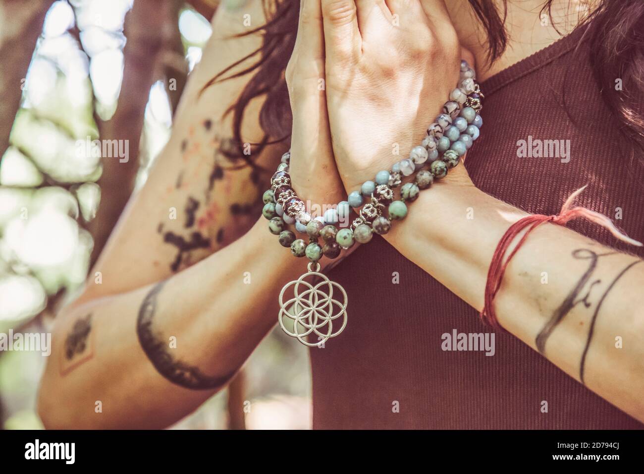 Female hands doing namaste mudra yoga practice in forest with mala ...