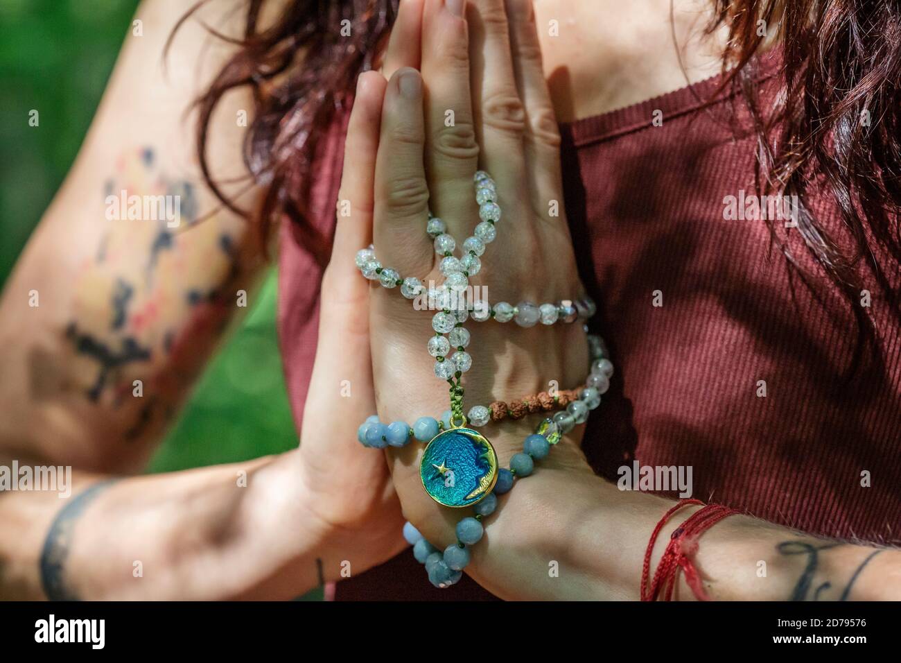 Female hands doing namaste mudra yoga practice in forest with mala ...
