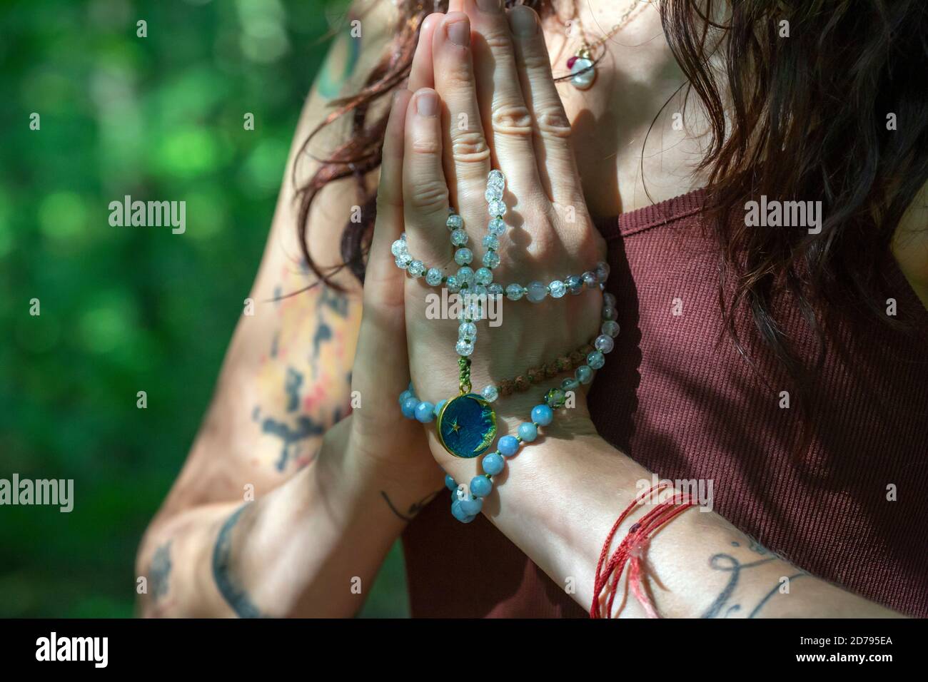 Female hands doing namaste mudra yoga practice in forest with mala ...