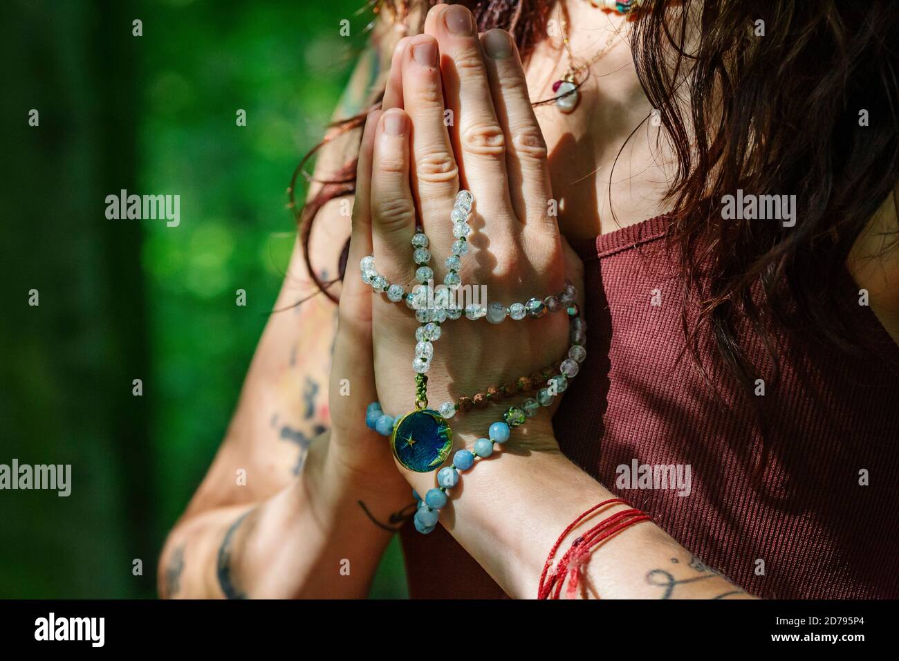 Female hands doing namaste mudra yoga practice in forest with mala ...