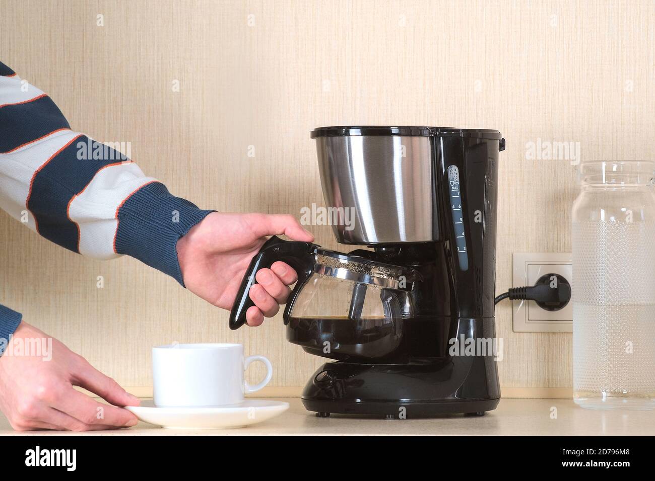 Coffee area in the office. The Manager pours a Cup of coffee from a ...