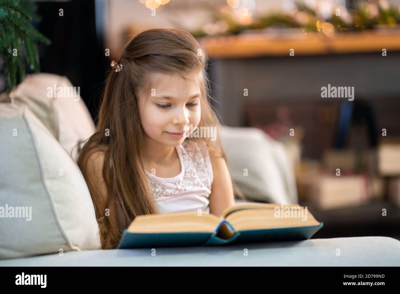 A little girl is reading an interesting book. Education and leisure of ...