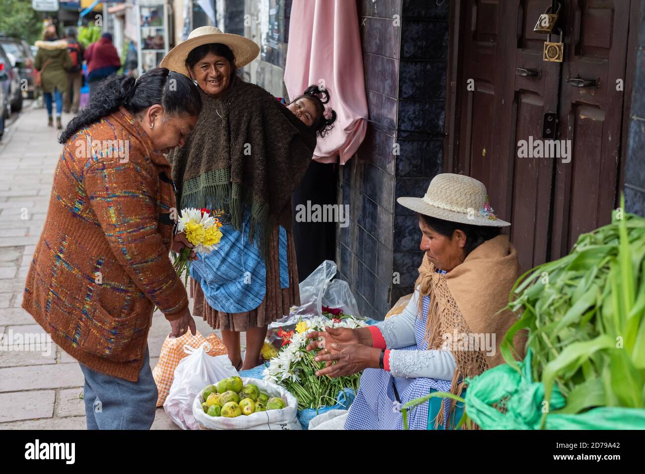 February 24, 2020: Women wearing traditional clothes and selling flowers and vegetables on the ...