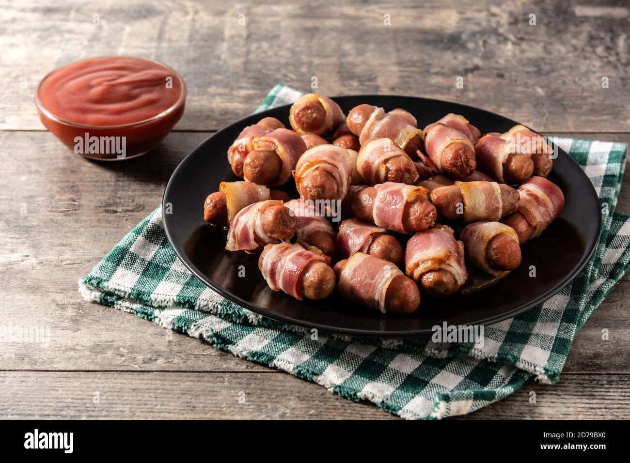Pig in blankets. Sausages wrapped in smoked bacon on wooden table Stock ...