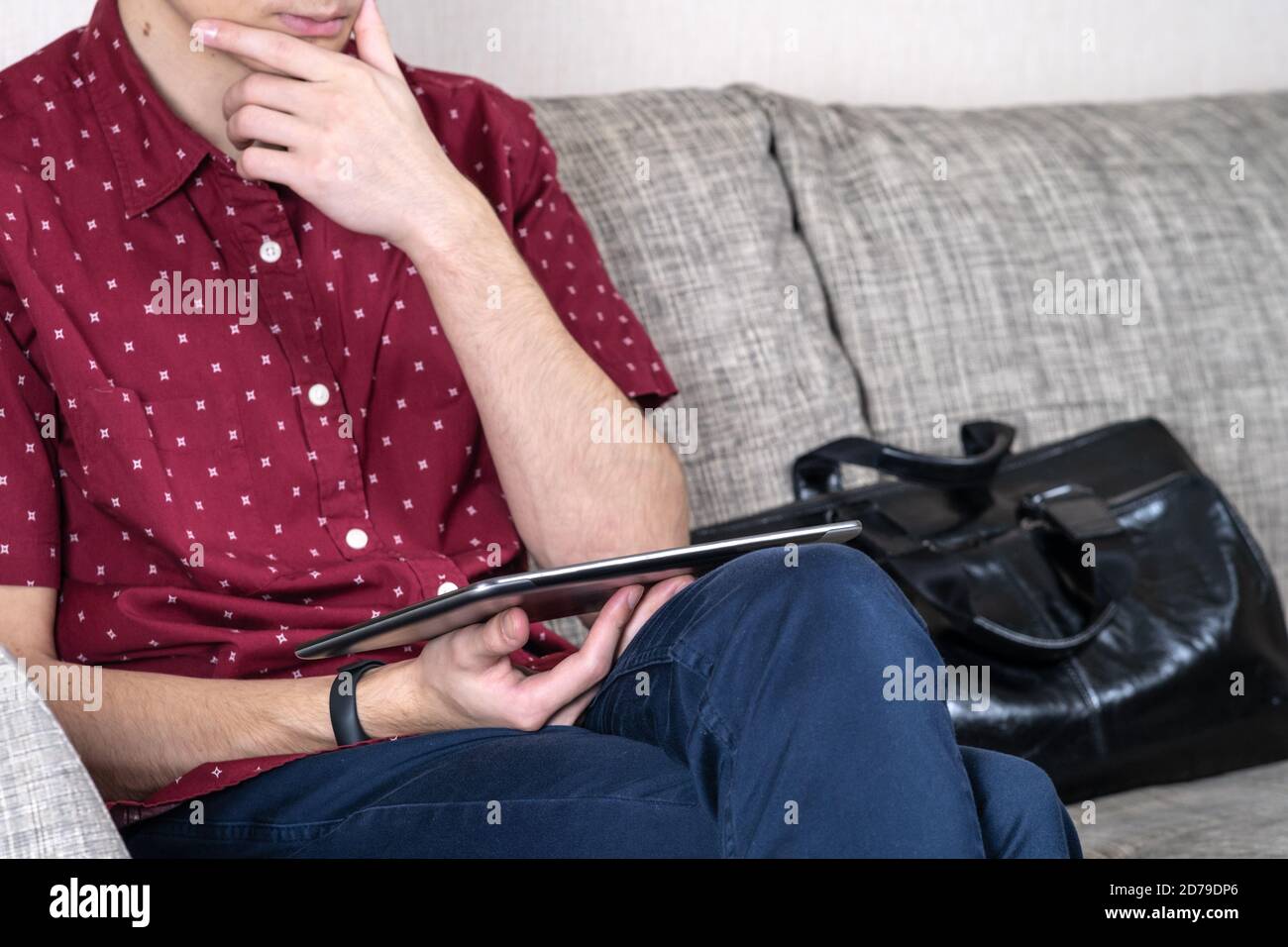 The young man sat down on the sofa in the office with his legs crossed ...