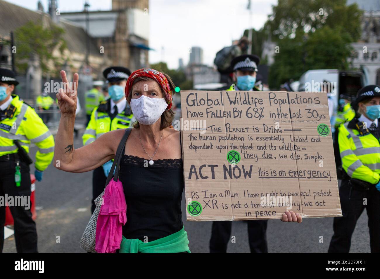 Protester with placard makes the peace sign in front of police ...